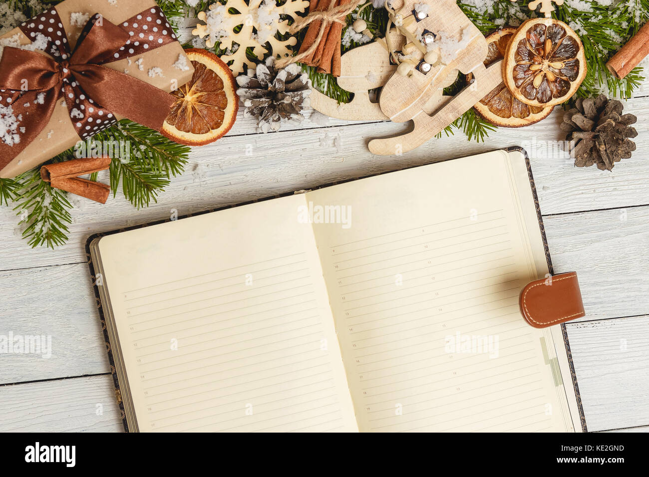 Christmas ornaments and an open blank notebook on a light wooden table ...