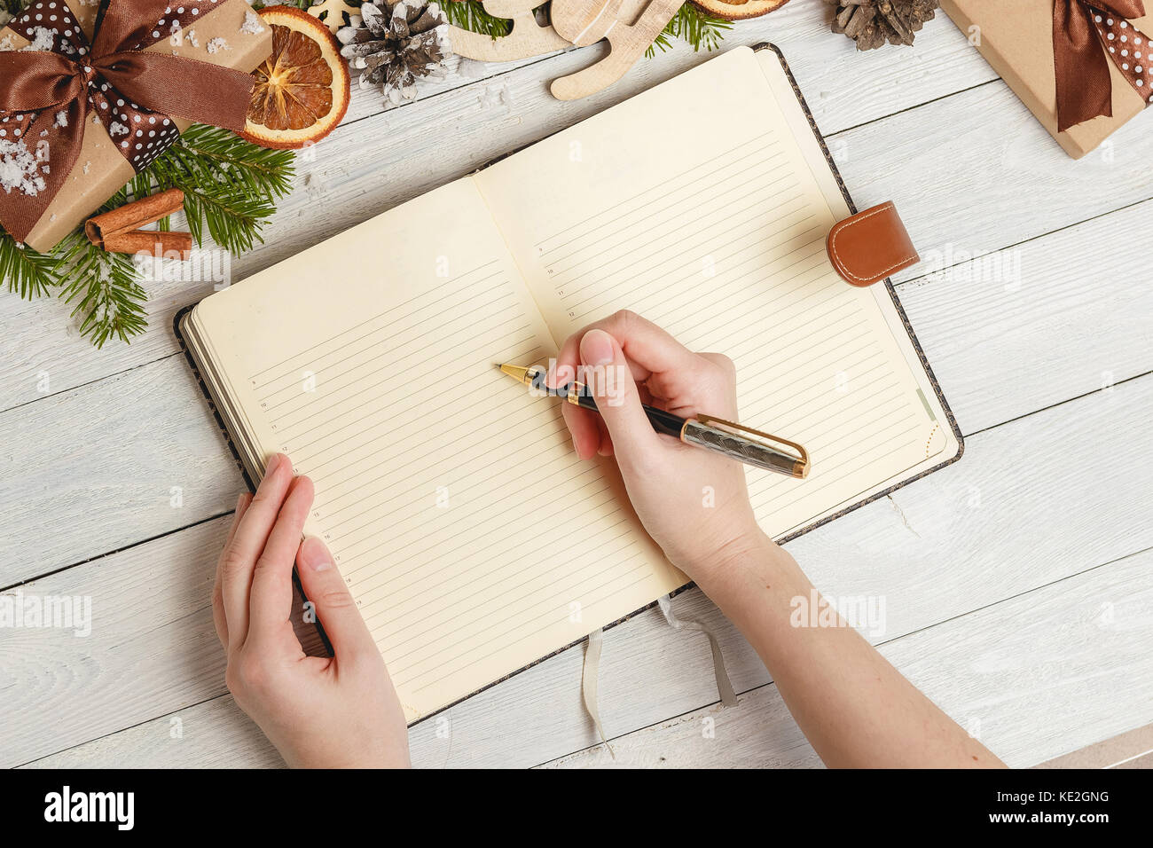 Christmas ornaments and an open blank notebook on a light wooden table ...