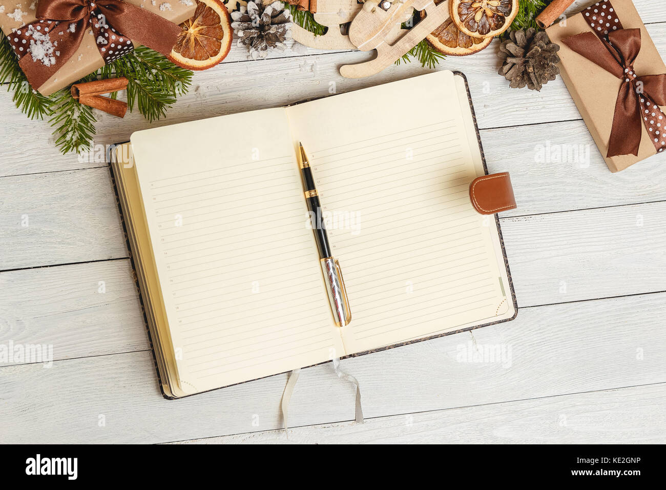 Christmas ornaments and an open blank notebook on a light wooden table ...