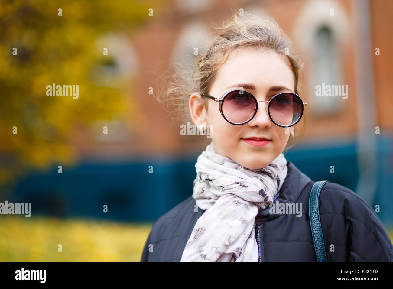 Young female student standing near college building in autumn ...