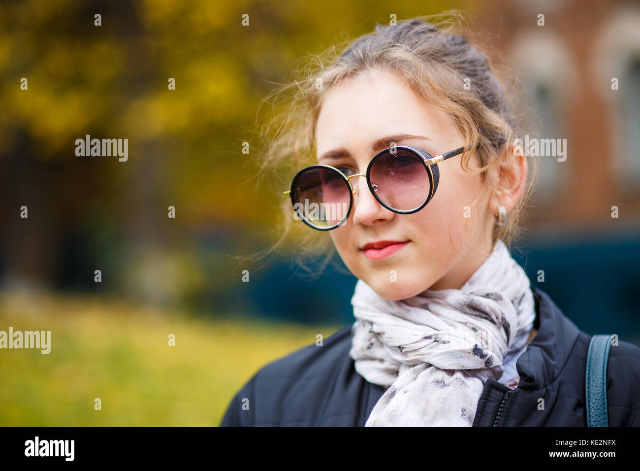 Young female student standing near college building in autumn ...