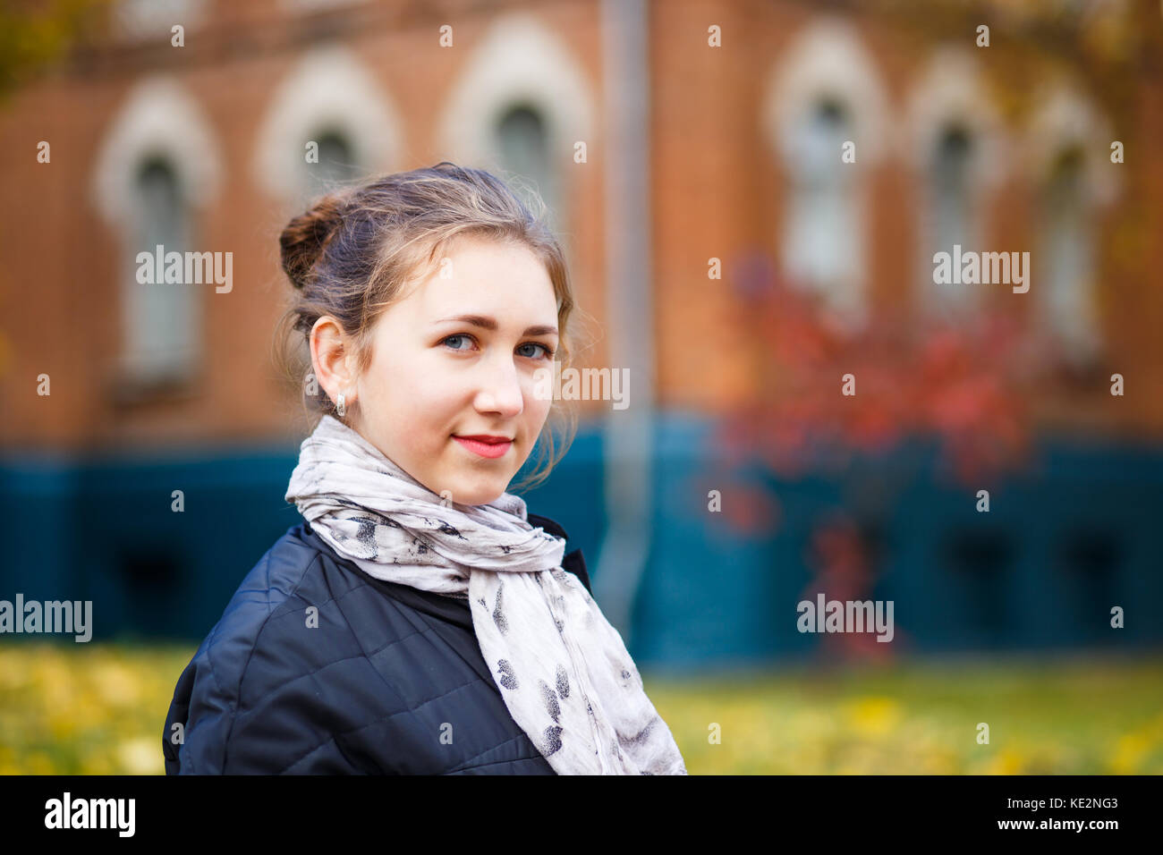 Young female student standing near college building in autumn ...