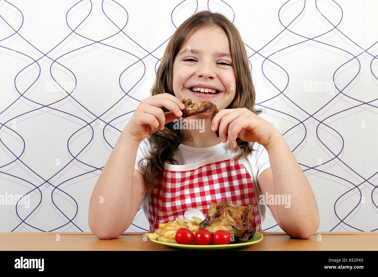 happy little girl eating chicken wings Stock Photo - Alamy