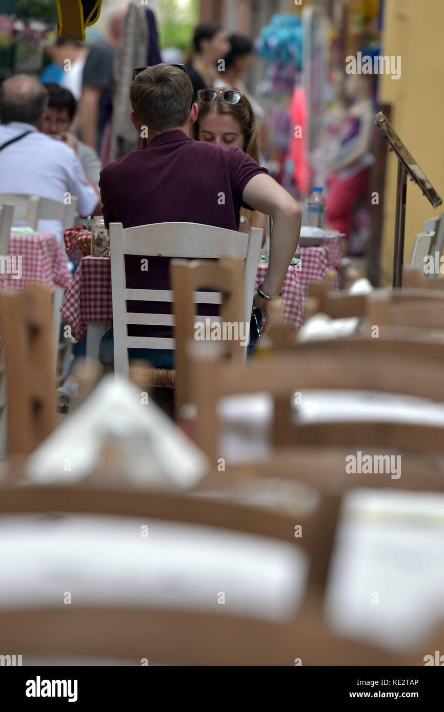 a young couple eating at a typical greek tavern in a crowded street in ...
