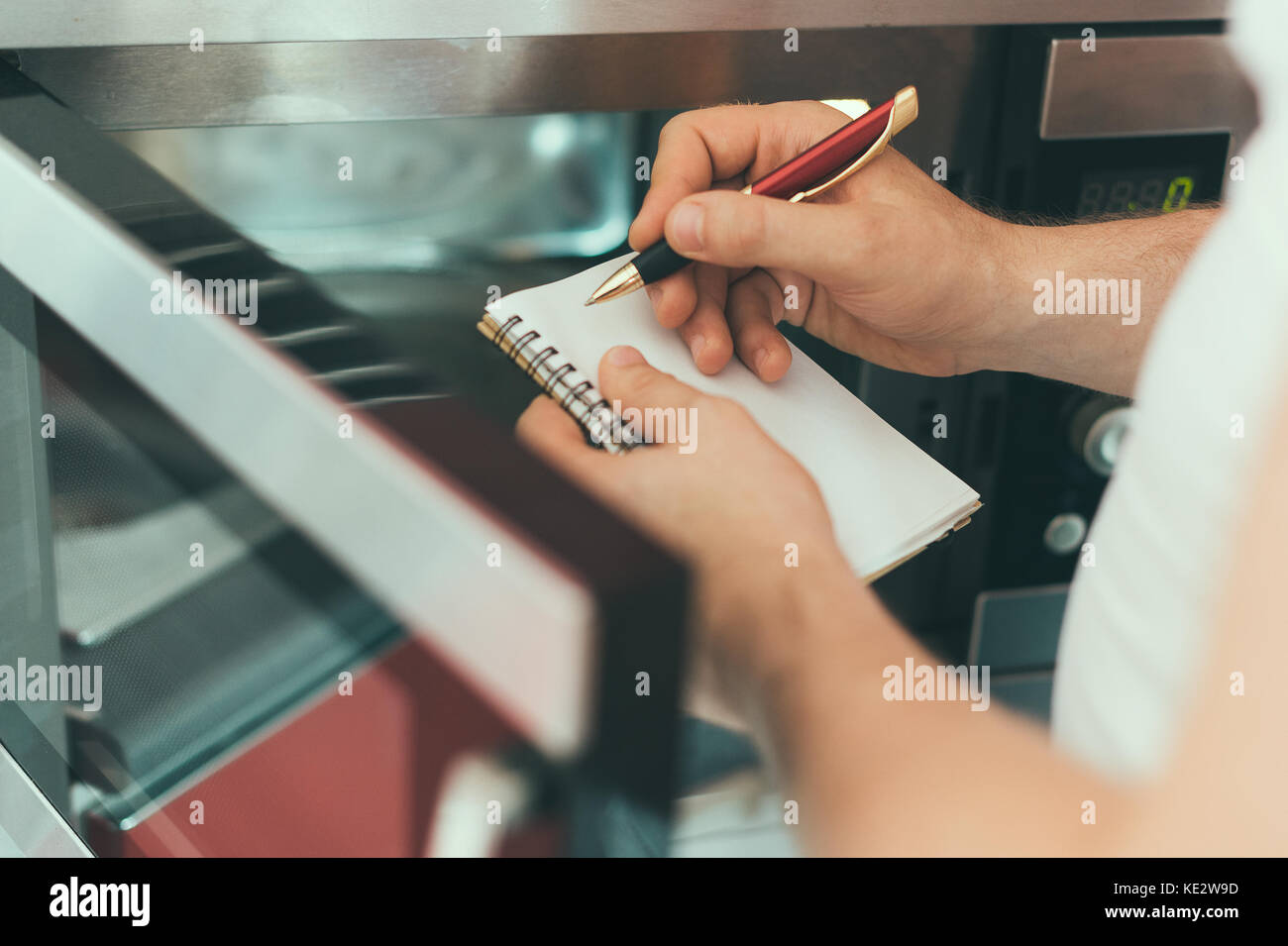 Male technician repairing microwave oven, writing the manufacturer's ...