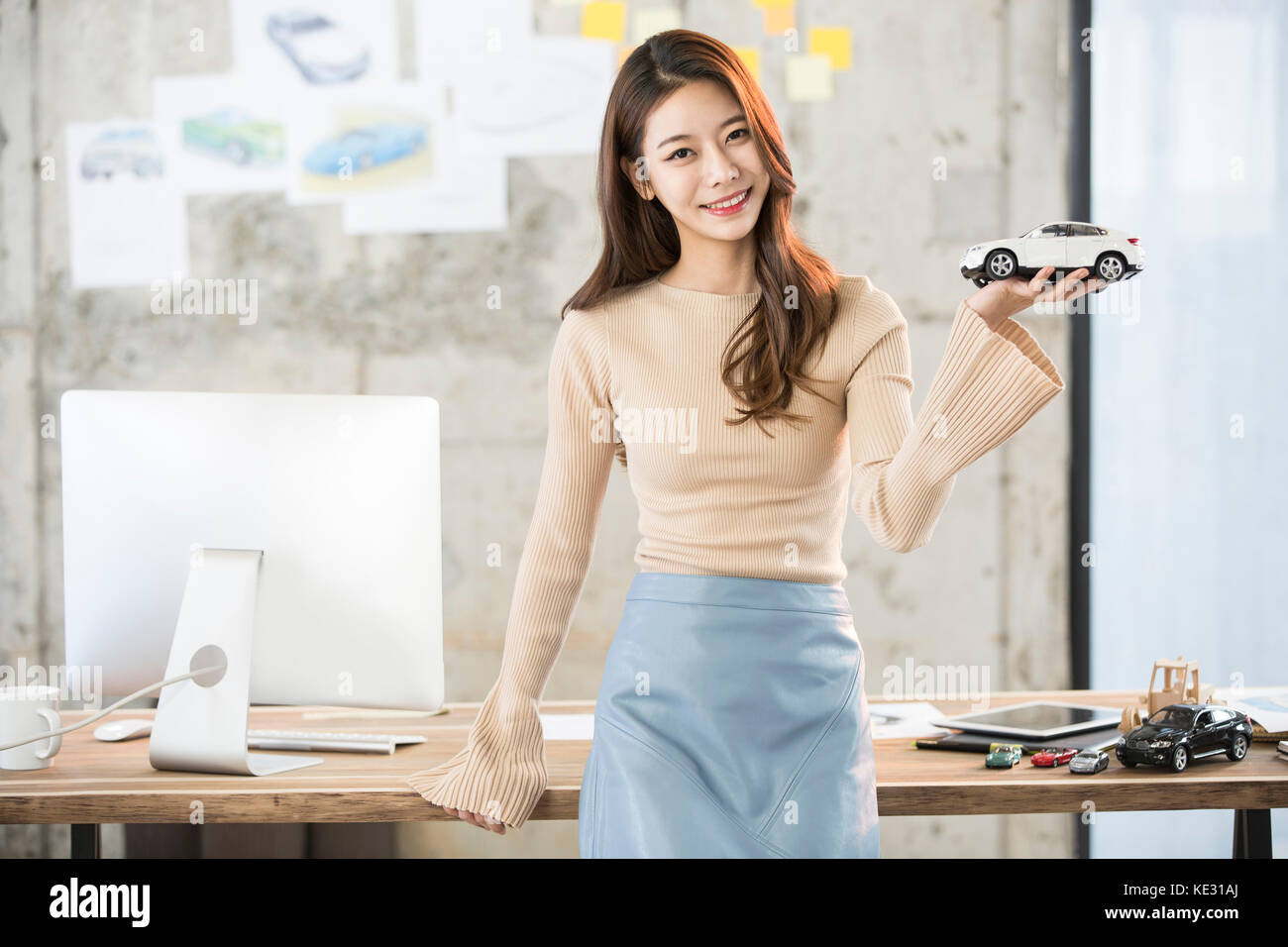 Young smiling female car designer holding a model car at work Stock ...