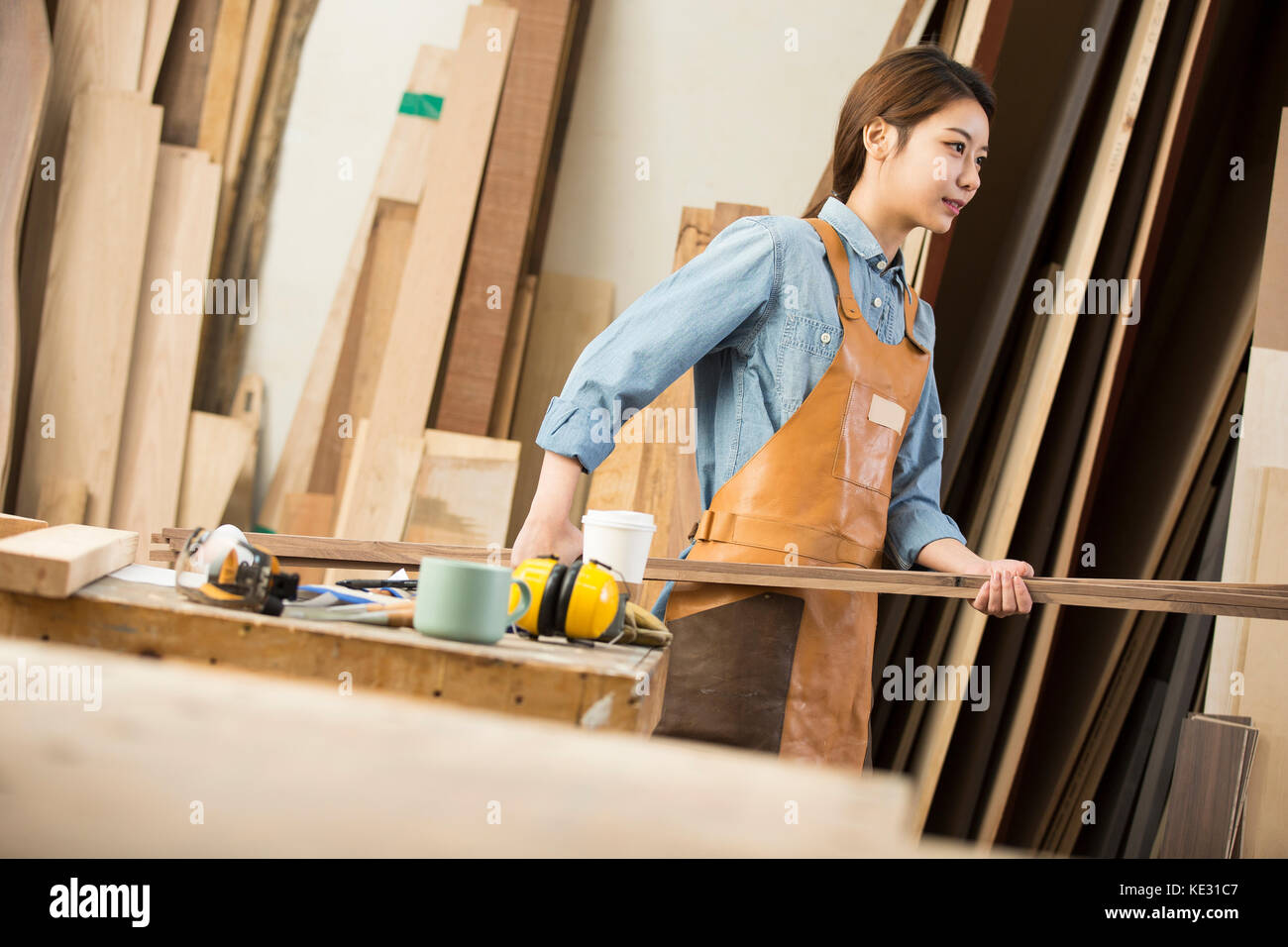 Side view of young female woodworker carrying wood Stock Photo - Alamy