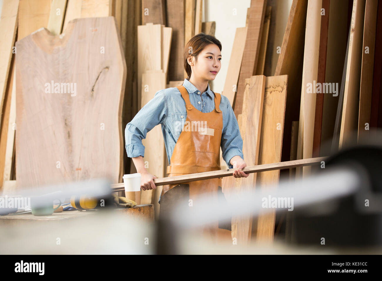 Side view of young female woodworker carrying plywood Stock Photo - Alamy