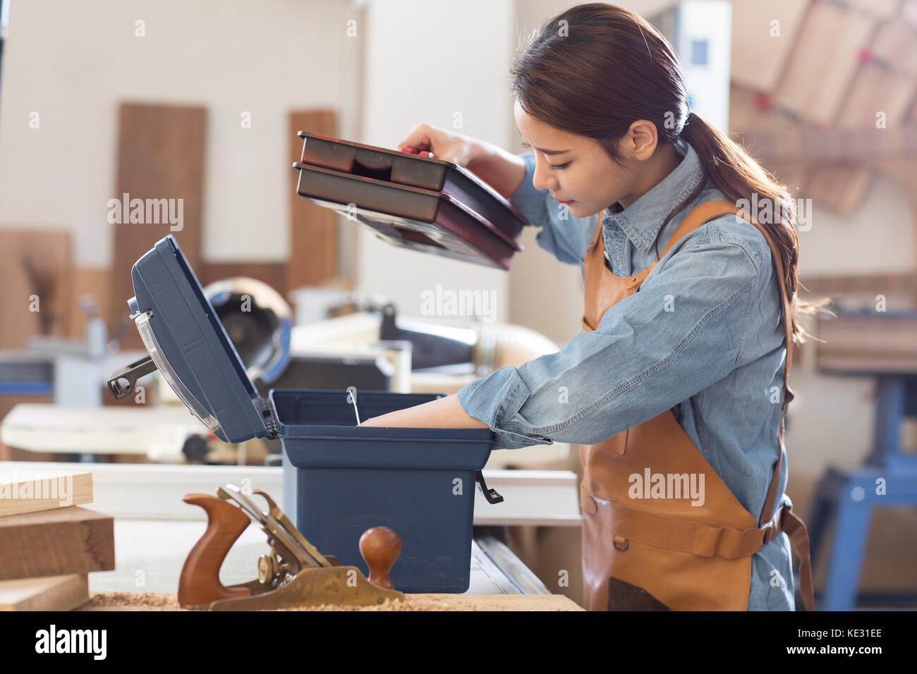 Side view of young female woodworker with tool box Stock Photo - Alamy