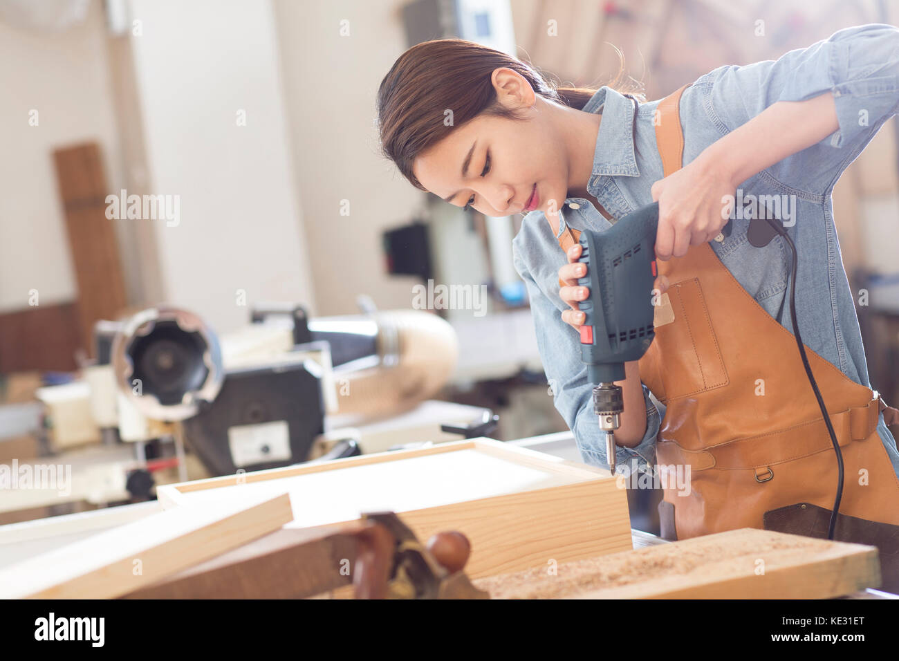 Side view of young female woodworker using a motor drill Stock Photo ...