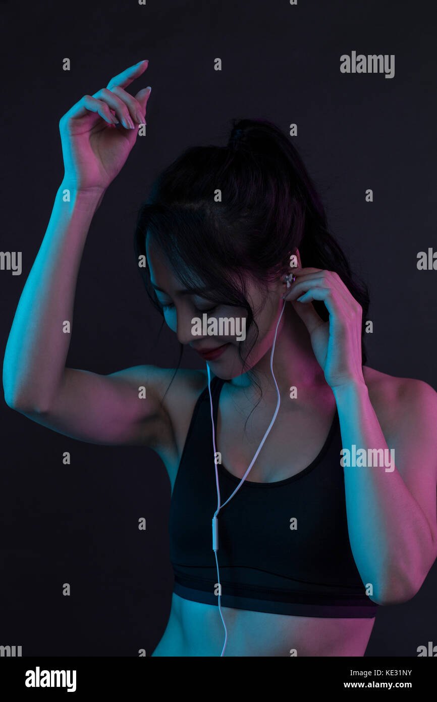 Portrait of young smiling slim woman in sports bra dancing listening to ...