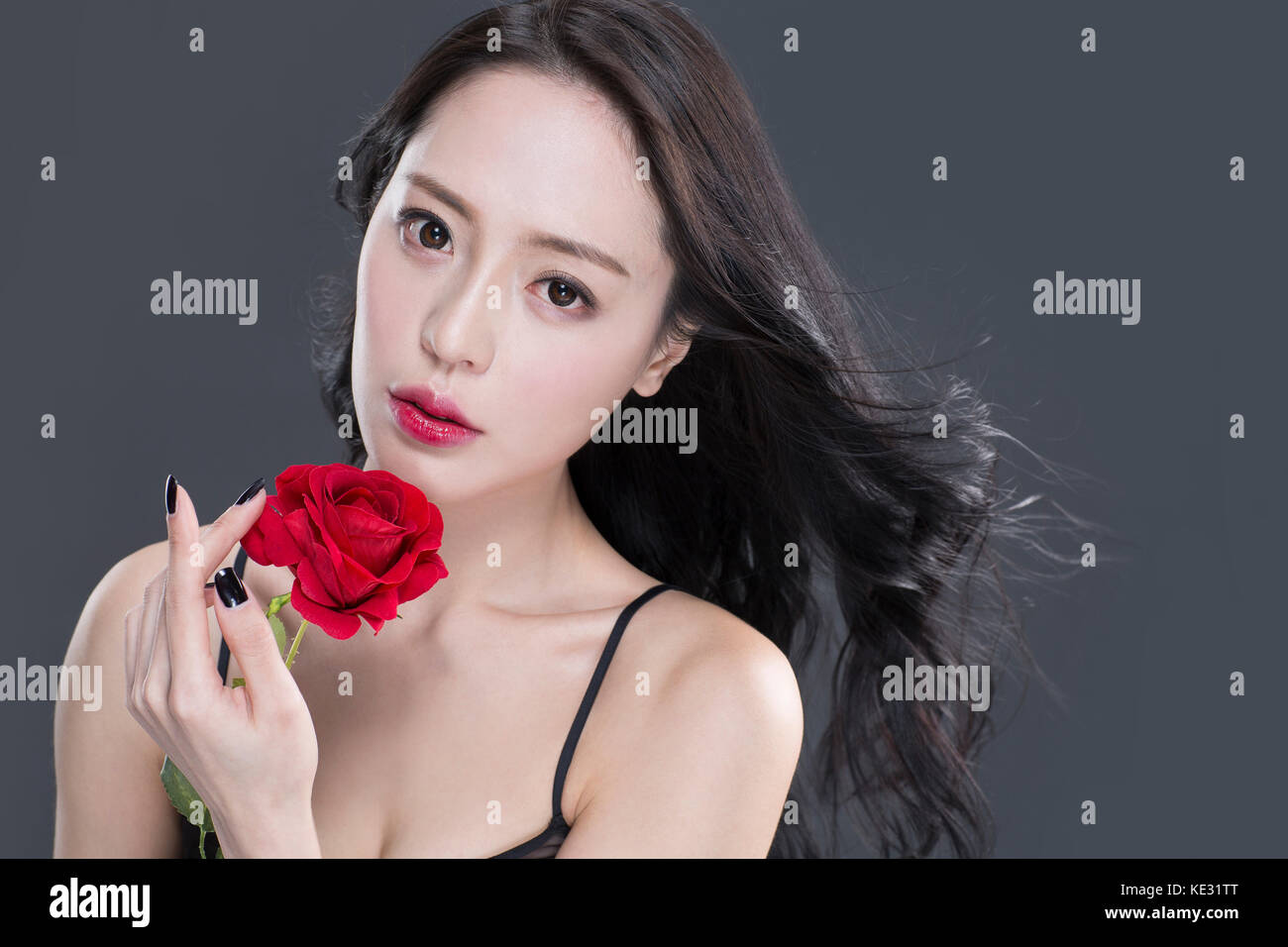 Portrait of young woman with red rose Stock Photo - Alamy