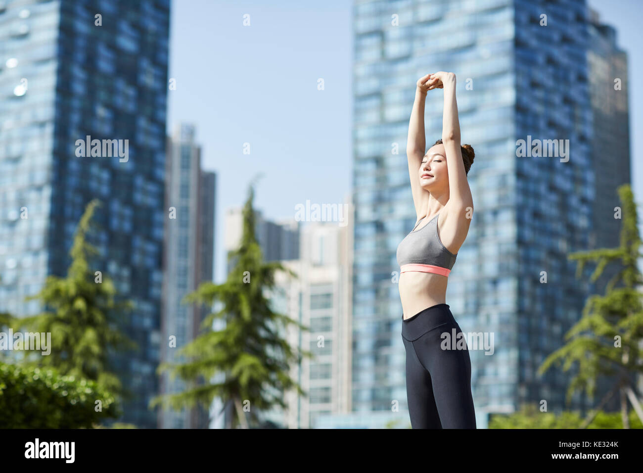 Side view of young smiling slim woman stretching Stock Photo - Alamy