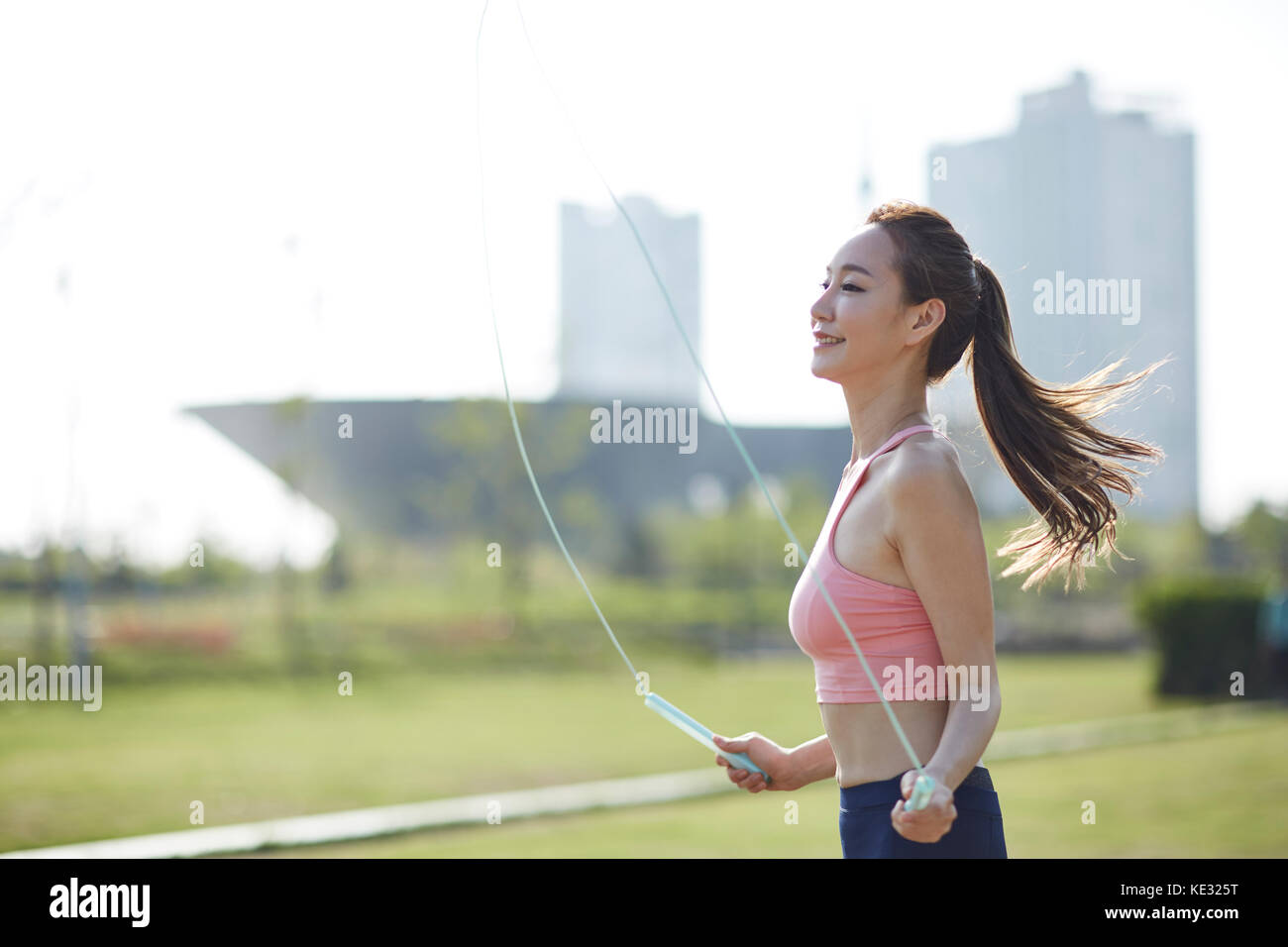 Side view of young smiling slim woman exercising with jump rope Stock ...
