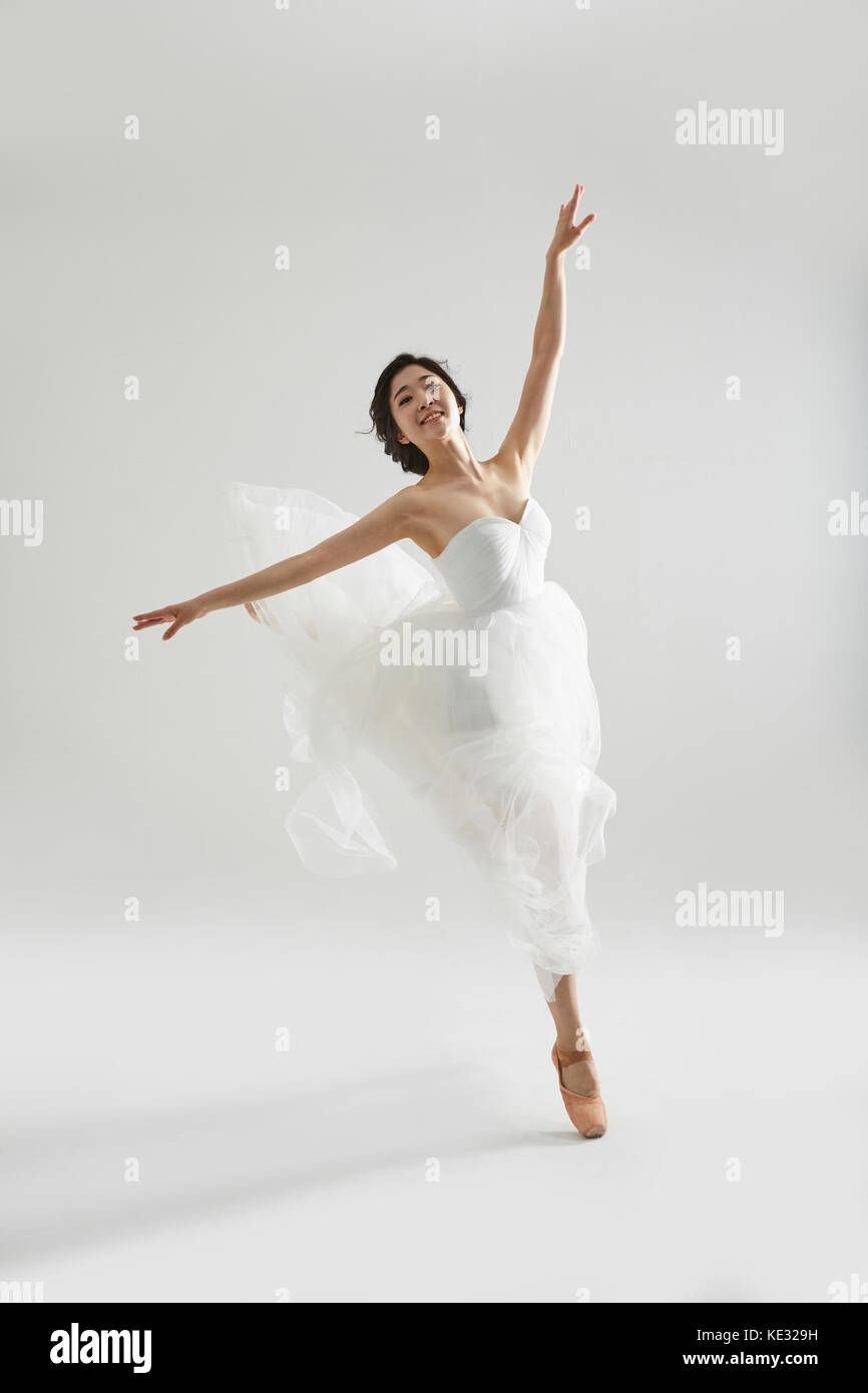 Young smiling ballerina in white dress posing elegantly Stock Photo - Alamy