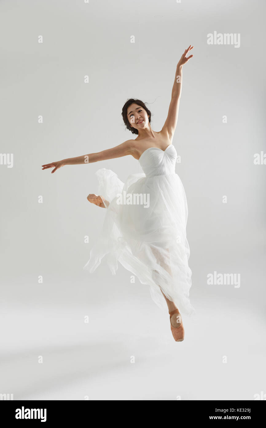 Young smiling ballerina in white dress posing elegantly Stock Photo - Alamy