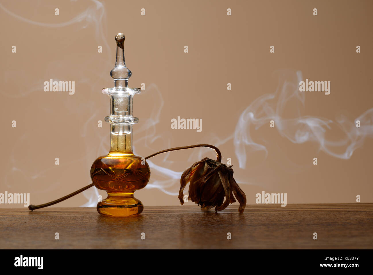 Small bottle of perfume on table decorated with dried flower and smoke ...