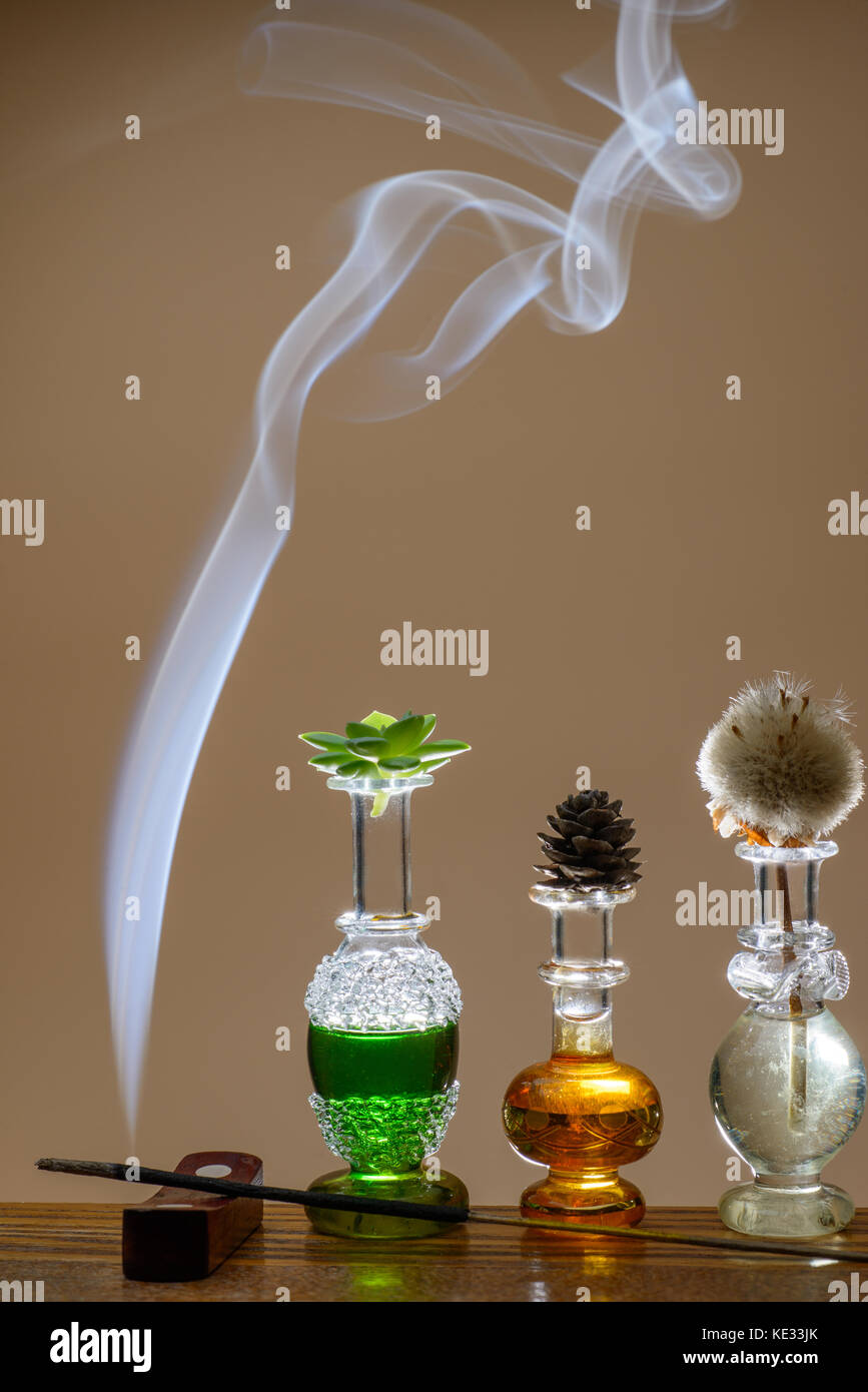 Small bottles of perfume dacorated with smoke from aromatic sticks ...