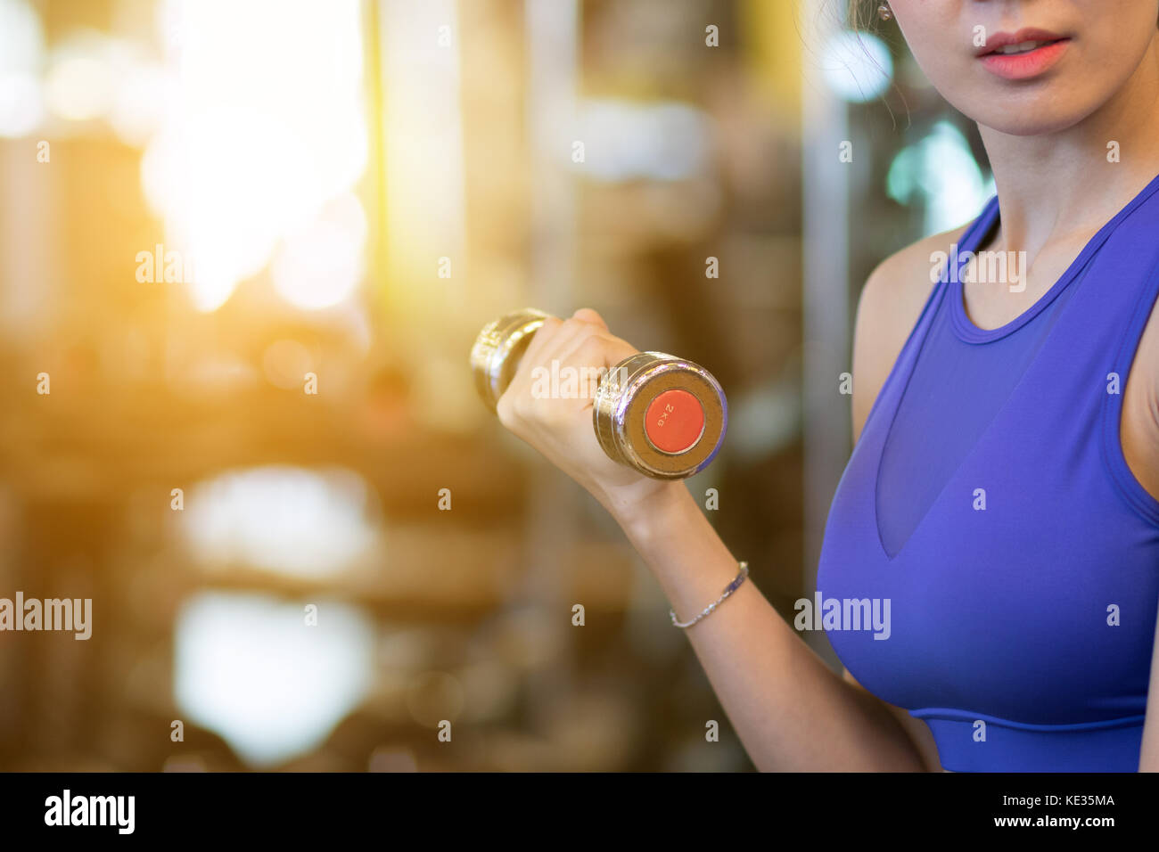 young woman execute exercise in fitness center. female athlete lift dumbbell in gym. sporty ...