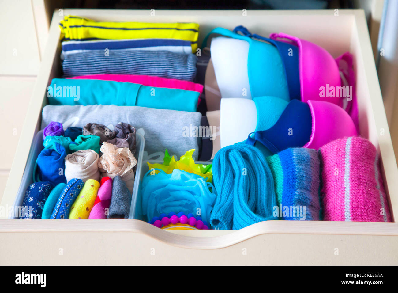 Neatly folded clothes with accessories in chest of drawers Stock Photo ...
