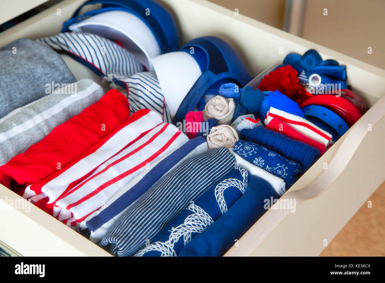 Neatly folded clothes with accessories in chest of drawers Stock Photo ...