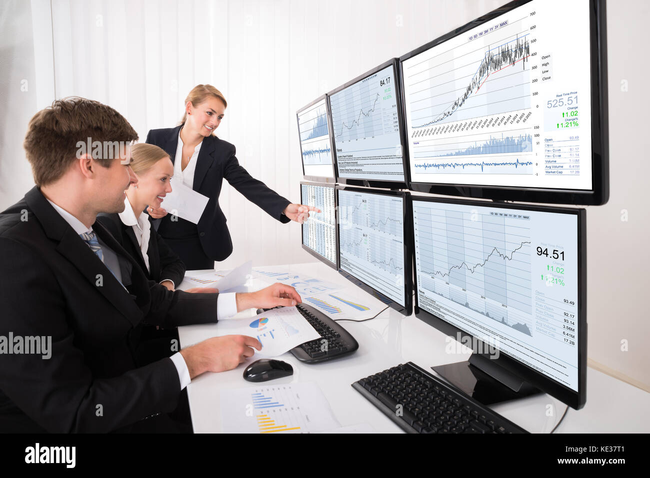 Happy Young Stock Market Brokers Looking At Graphs On Multiple Computer ...