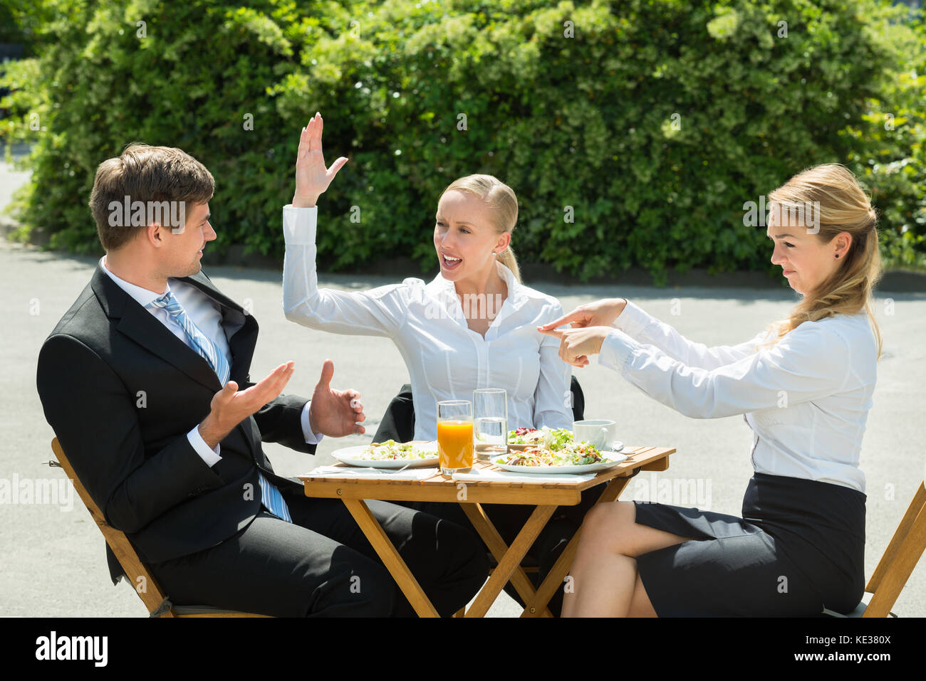 Businesspeople Having Argument In Restaurant With Food And Glass Of ...