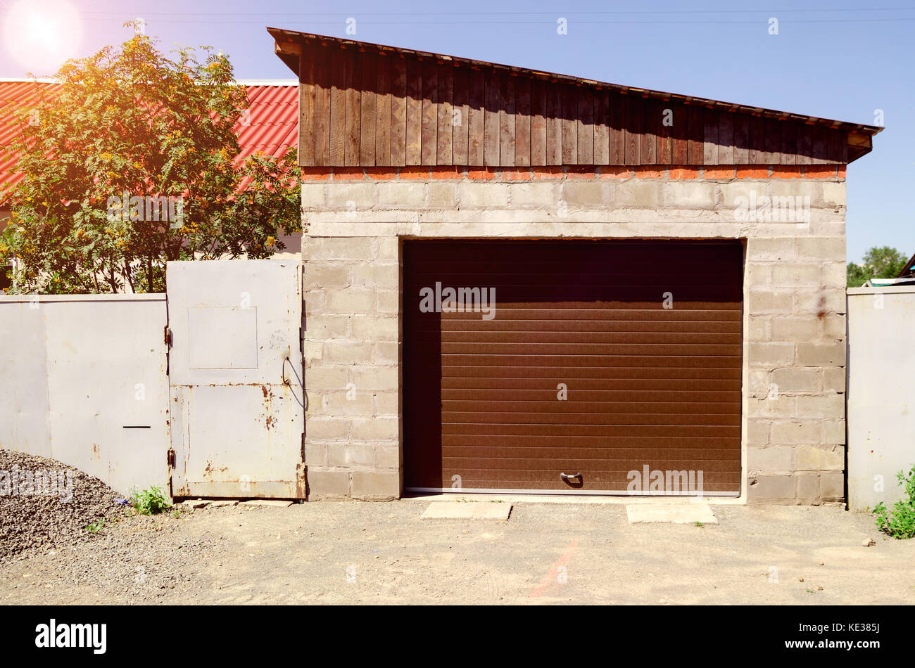 Stone garage with roller blinds door near the house in the sunny day ...