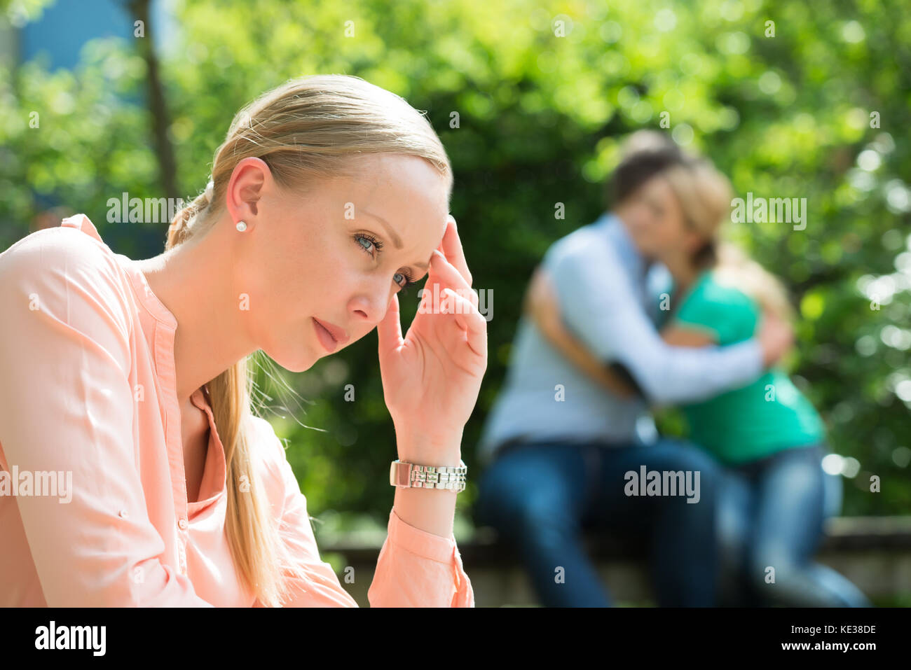 Close-up Of Depressed Young Woman In Front Of Couple Embracing Each ...
