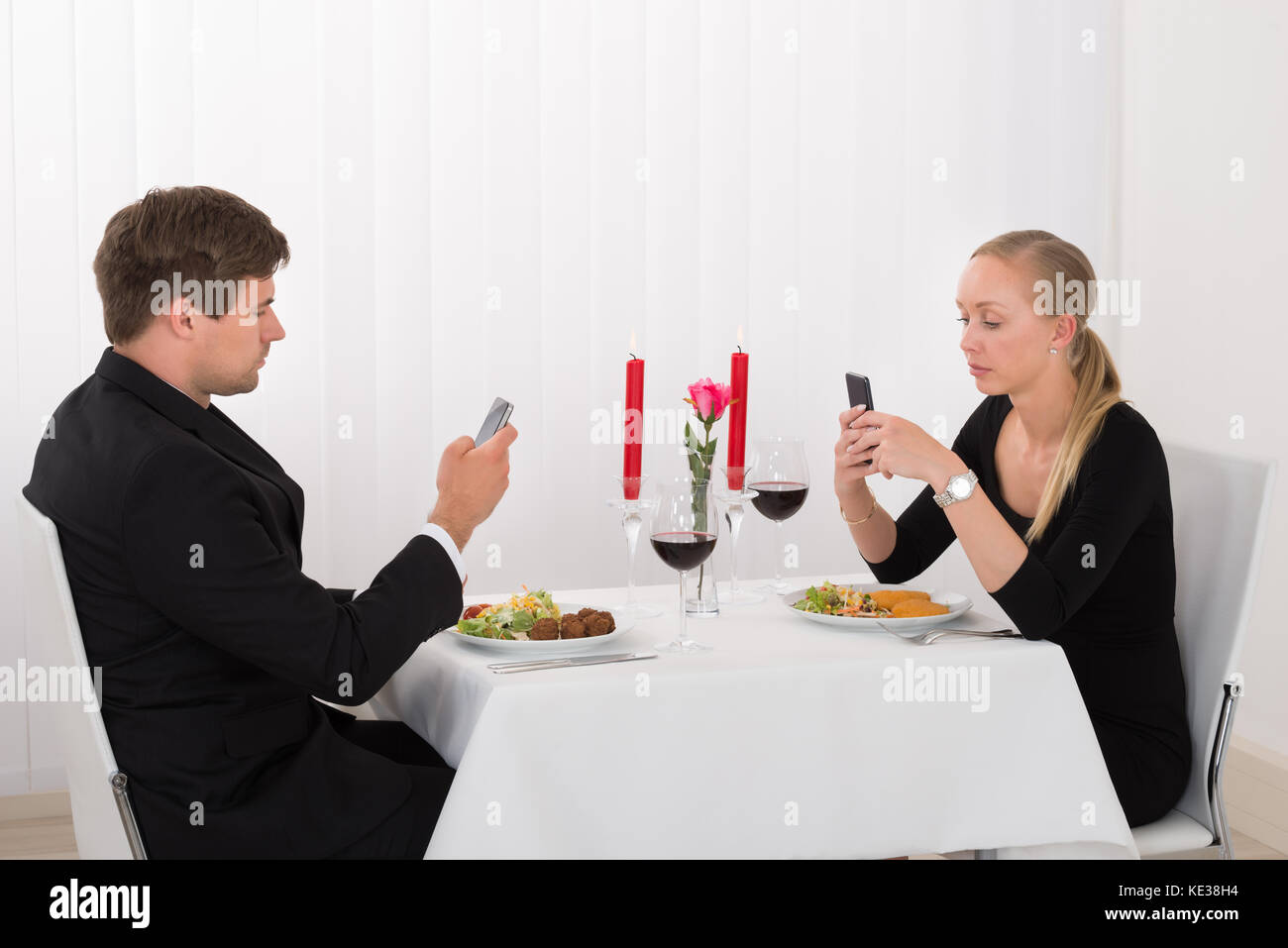 Couple Looking At Their Mobile Phones In Restaurant Stock Photo - Alamy