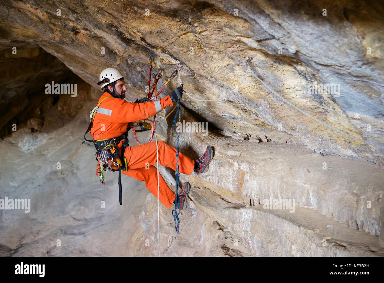 Speleologist performing rope maneuvers in a cave. Zaragoza Province ...