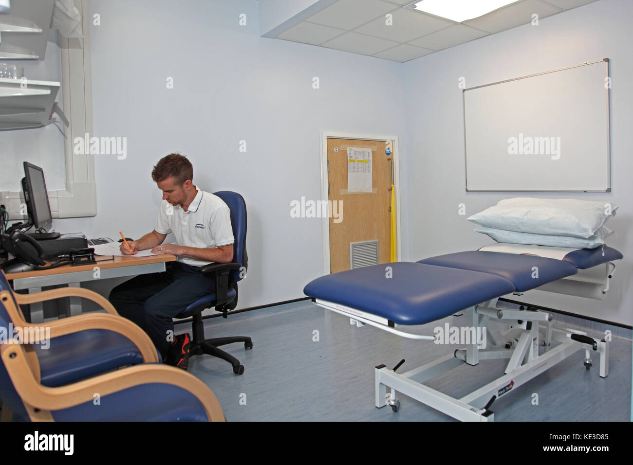A young, male physiotherapist works at his desk in a hospital treatment ...