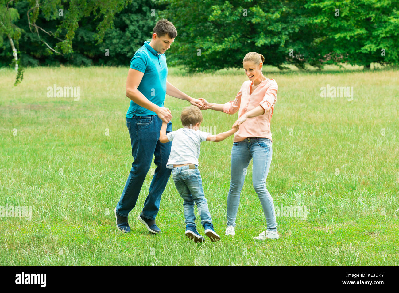 Happy Young Family Holding Each Other Hands While Playing In The Park ...