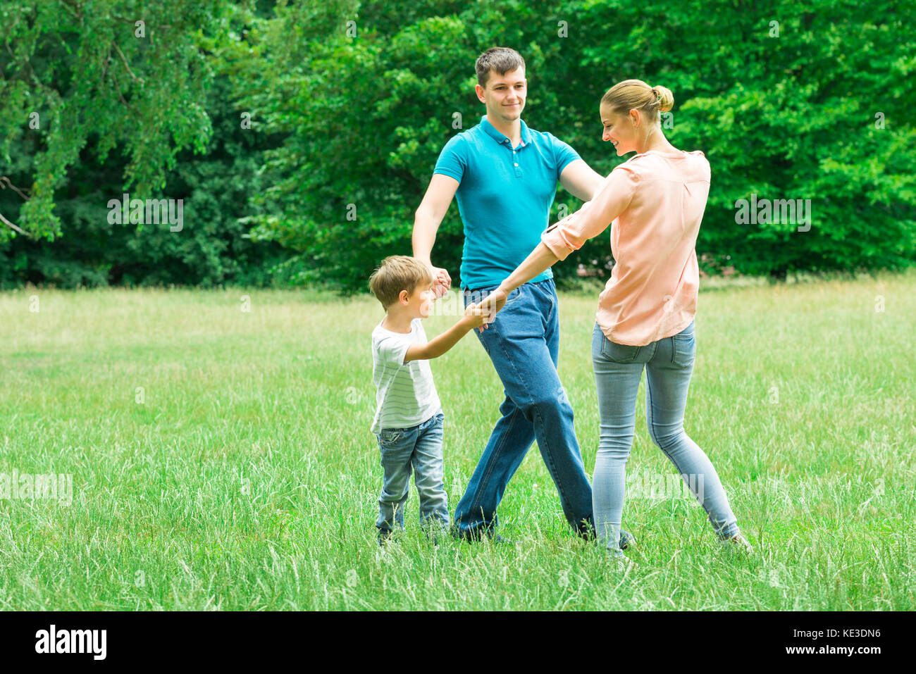 Happy Young Family Holding Each Other Hands While Playing In The Park ...