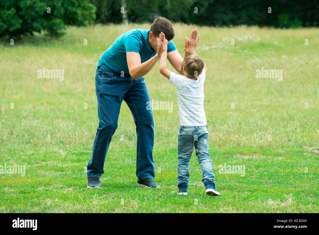 Little Boy Giving High Five To His Father In Park Stock Photo - Alamy
