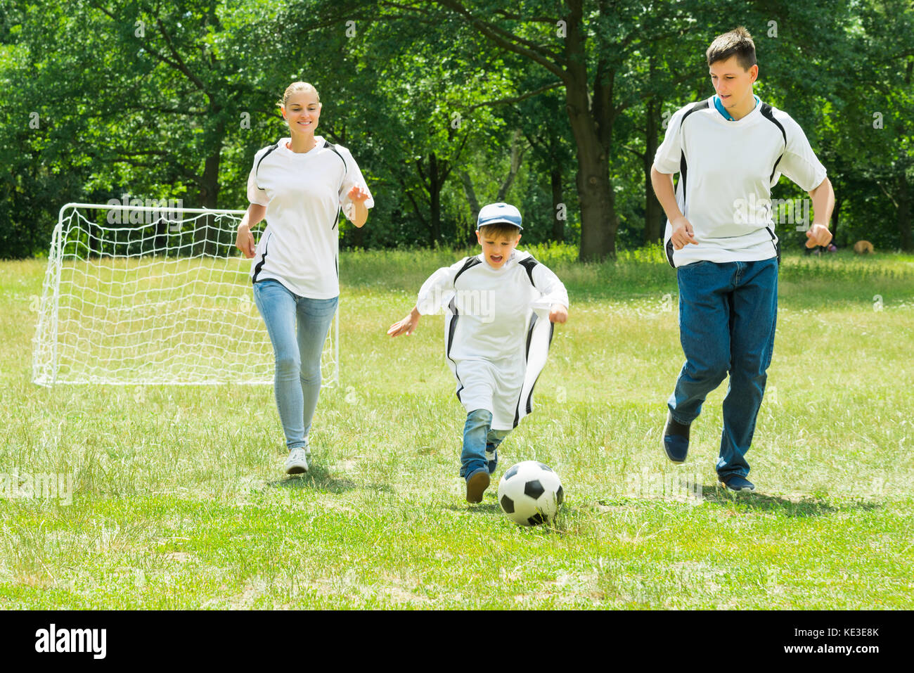 A Boy Playing Football With Their Parents In The Park Stock Photo - Alamy