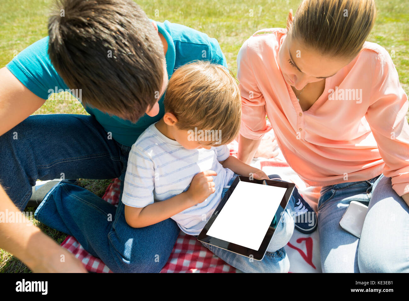 Elevated View Of A Parents Looking At Their Son Using Digital Tablet ...