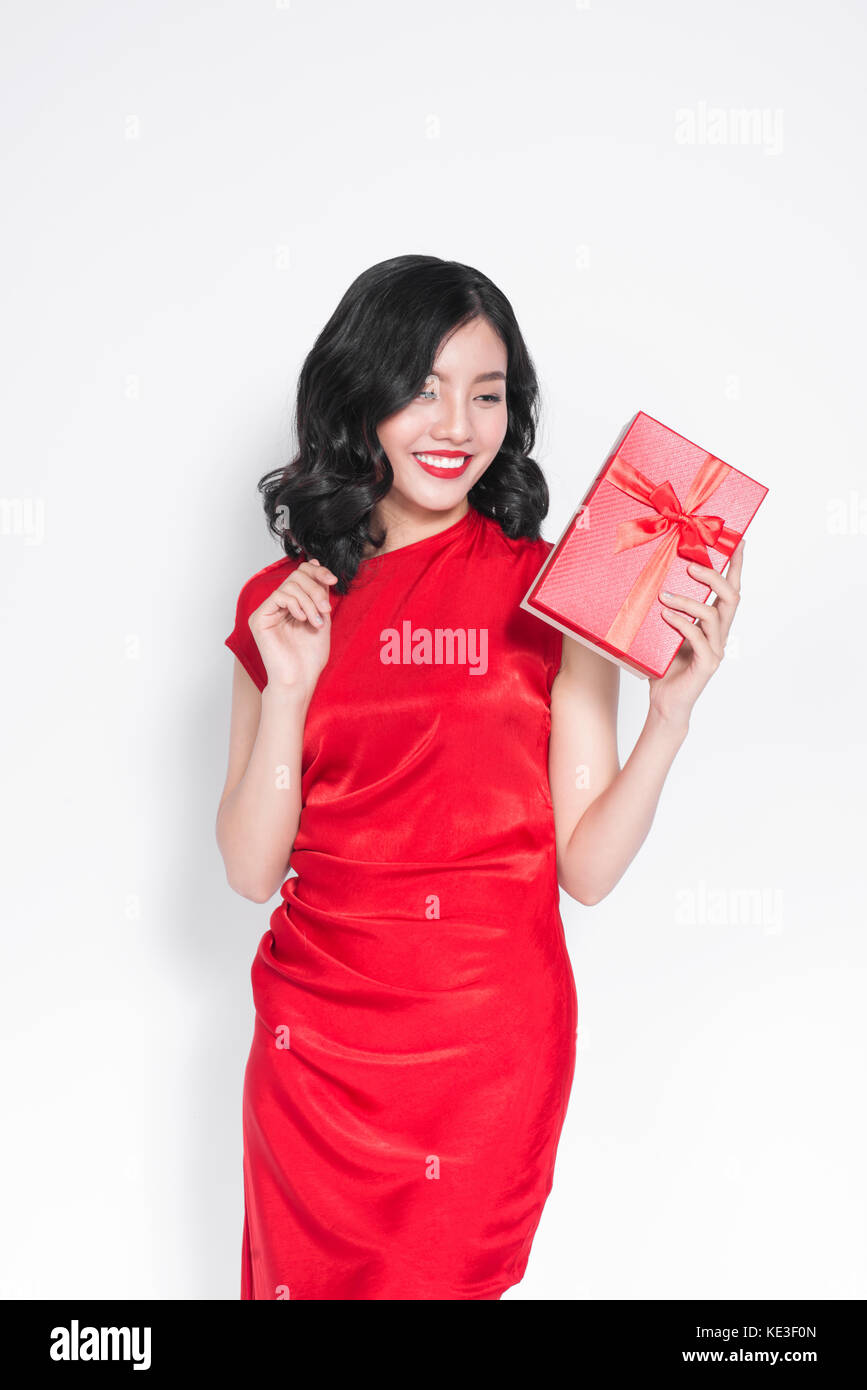 Pretty young glamorous asian woman dressed in red dress with a present ...