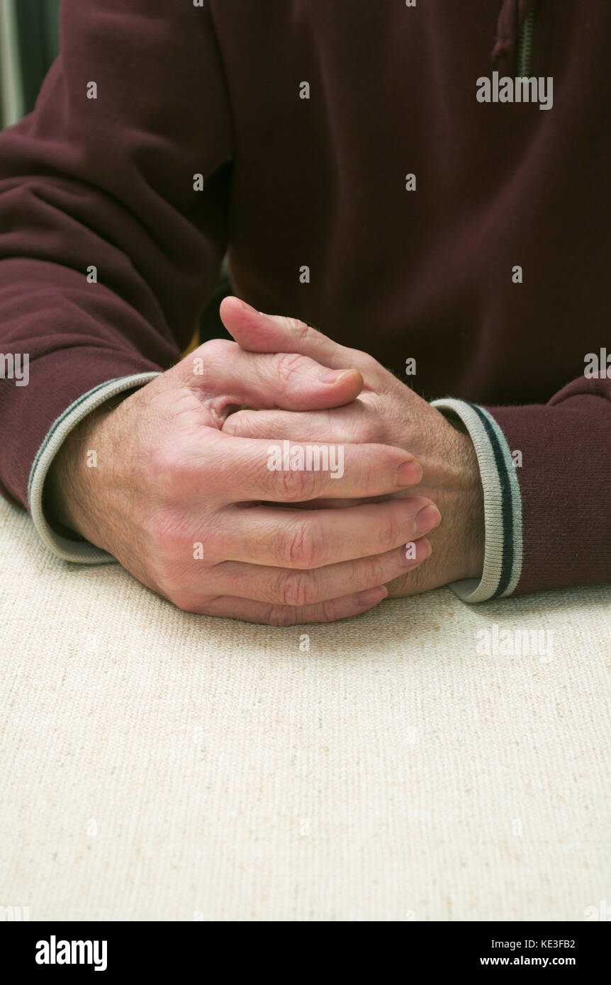 man at table with folded hands Stock Photo - Alamy