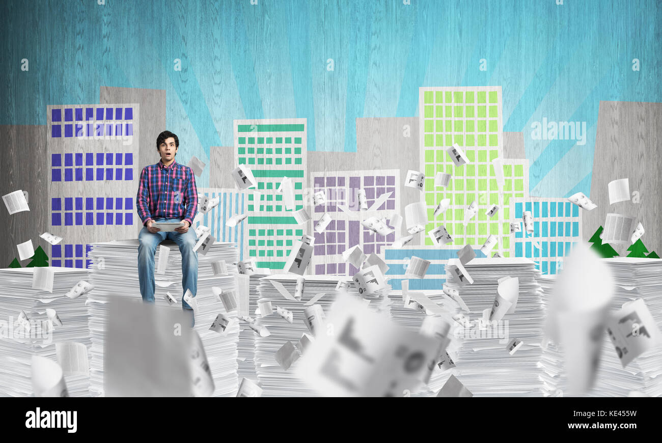 Young man sitting on pile of paper documents Stock Photo - Alamy