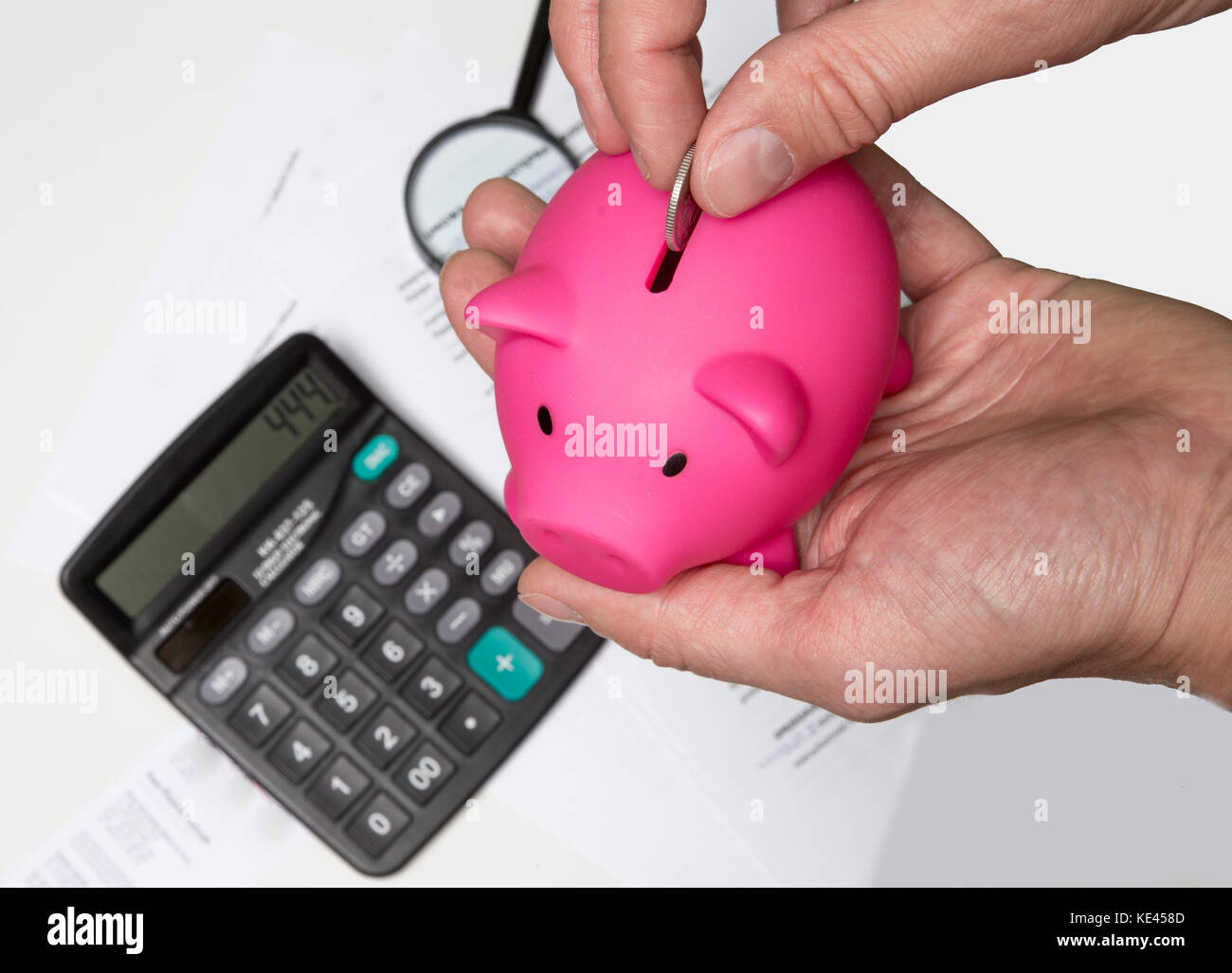 Man hand putting money to piggy bank - Stock image Stock Photo - Alamy