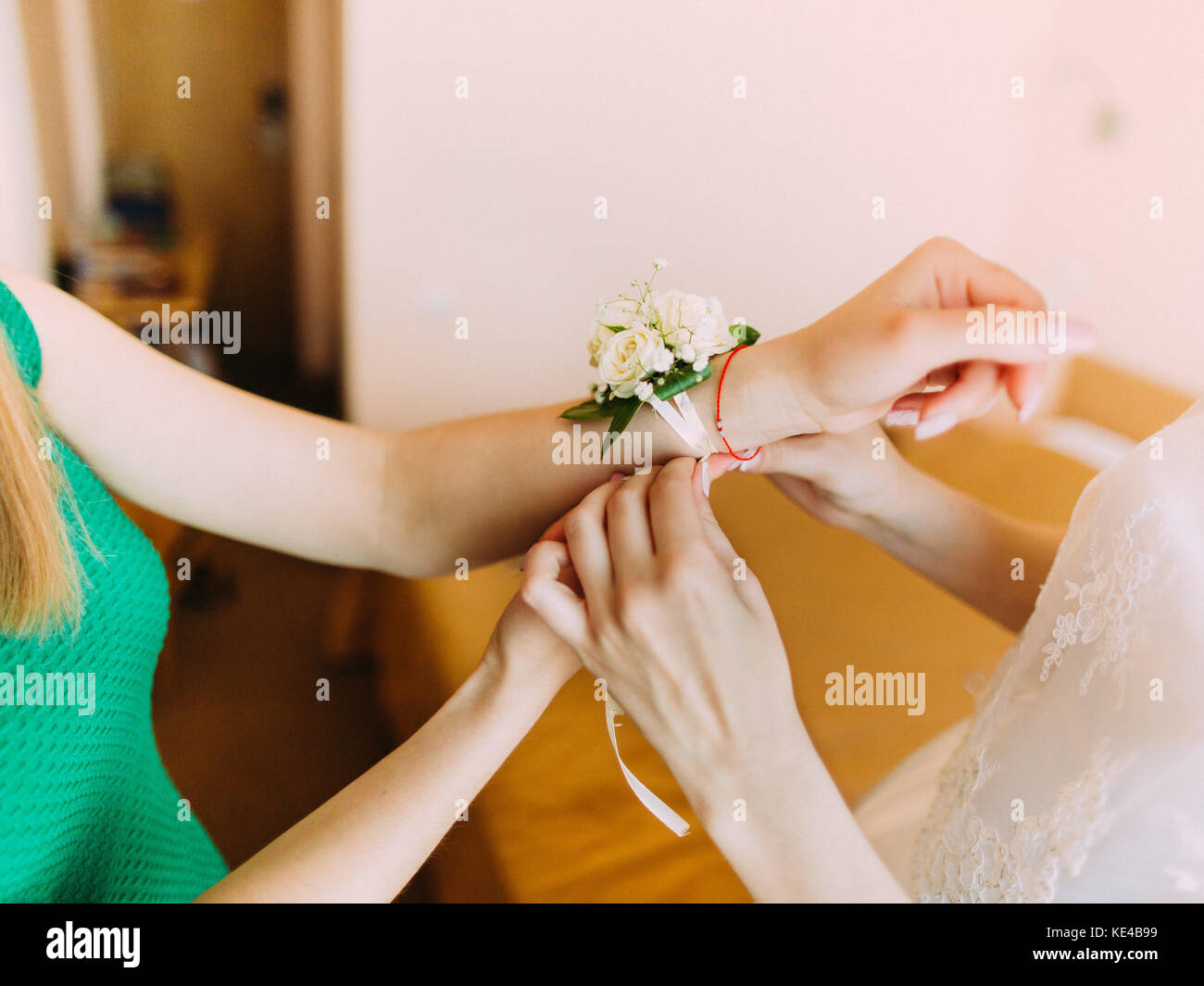 The close-up view of the bride`s hands tying the wedding wristband on ...