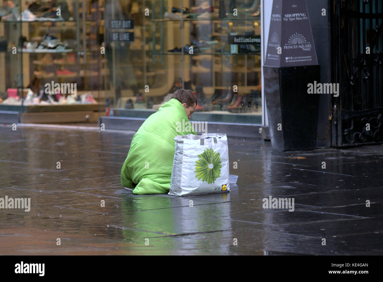 homeless man begging sitting in lime green sleeping bag with flower bag ...