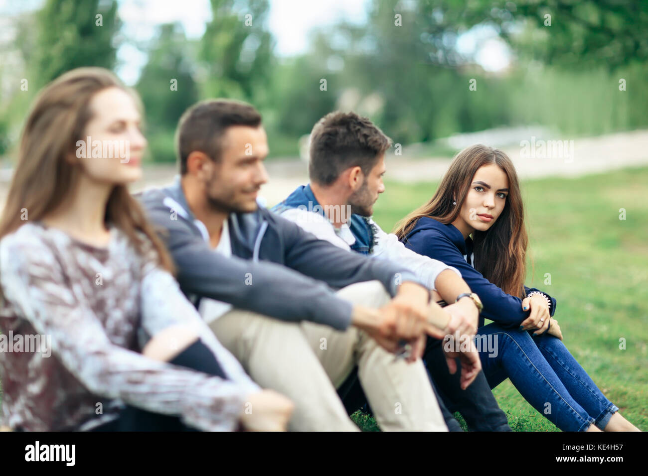 Young People Sitting On Grass In Lawn Closeup Group Of Vacationers In Nature Young Caucasian