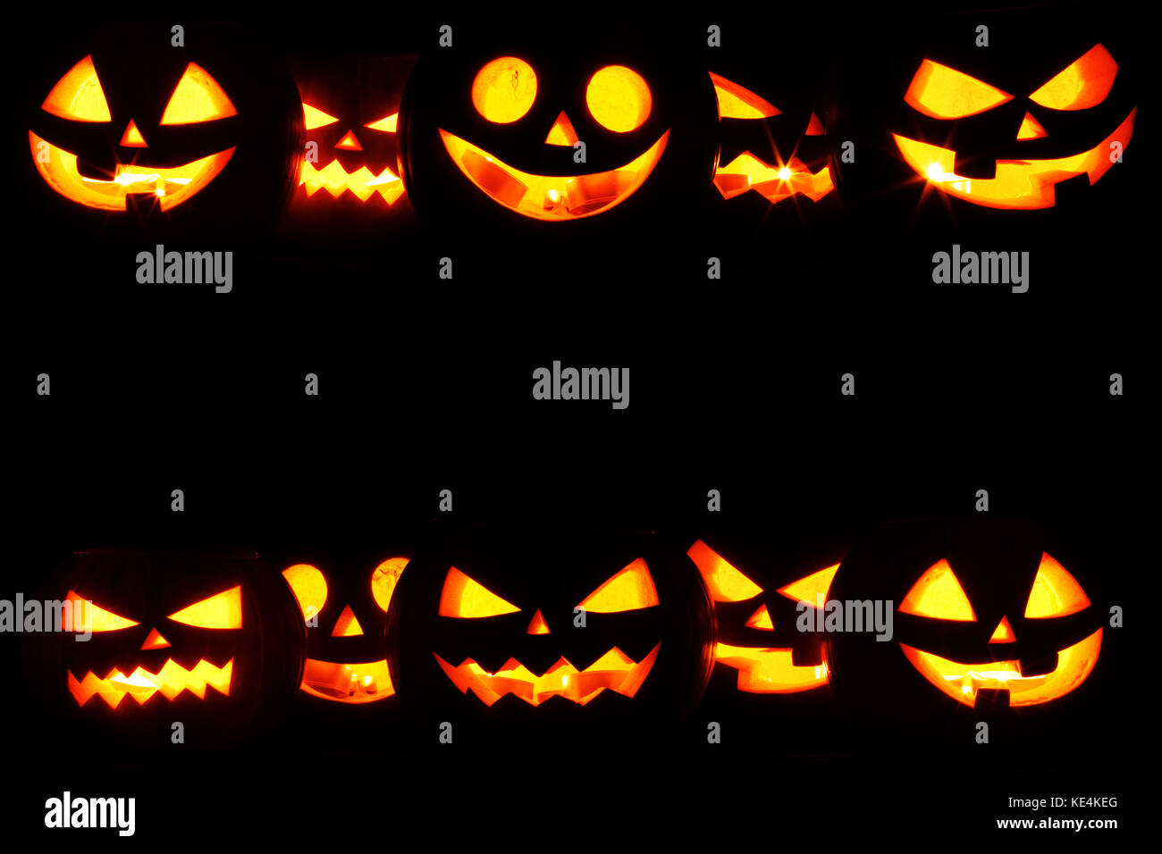 Many Halloween Pumpkin glowing faces in a row isolated on black ...