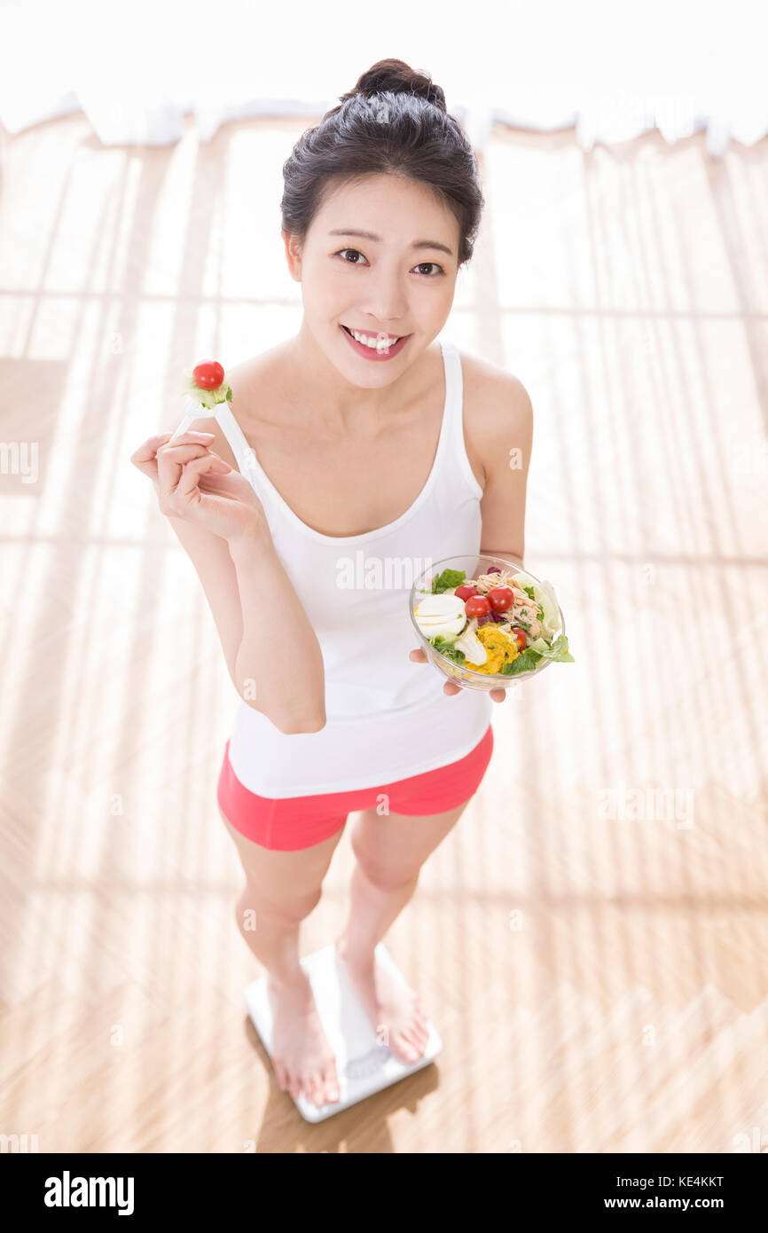 Young smiling slim woman with a bowl of salad standing on a scale Stock ...