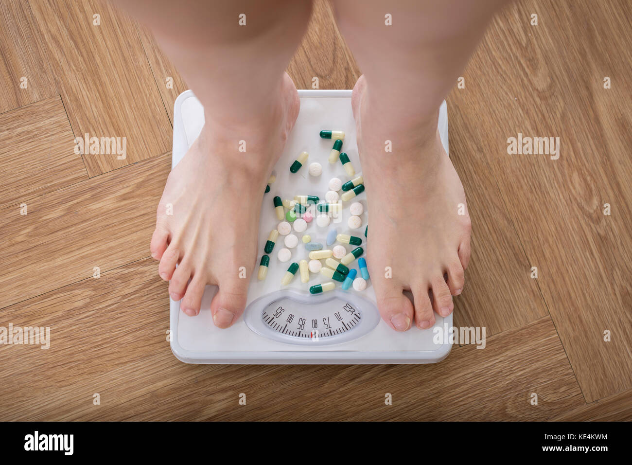 Feet on a scale with pills Stock Photo - Alamy