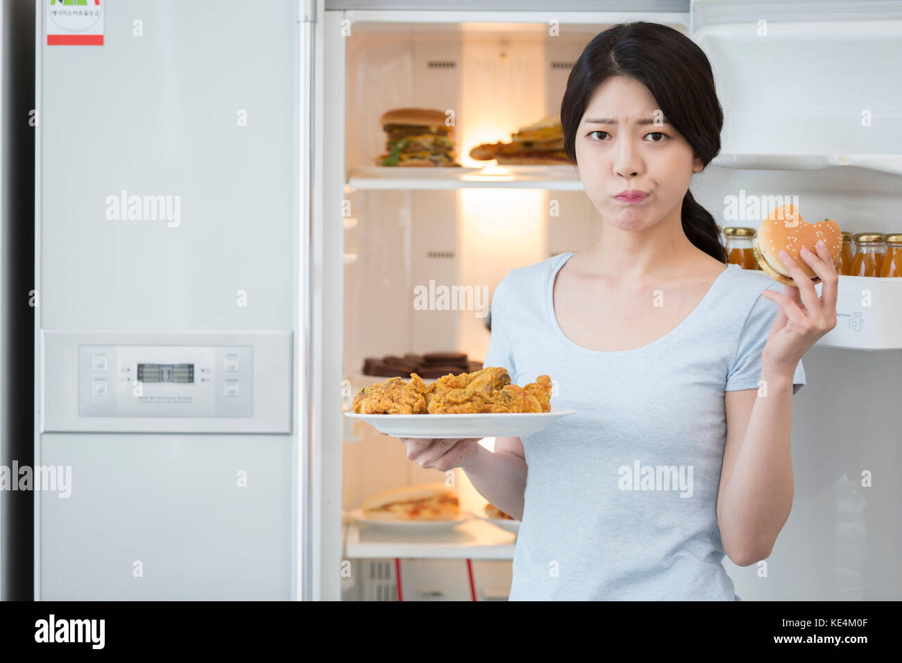 Portrait of young woman eating fast food frowning her face Stock Photo ...