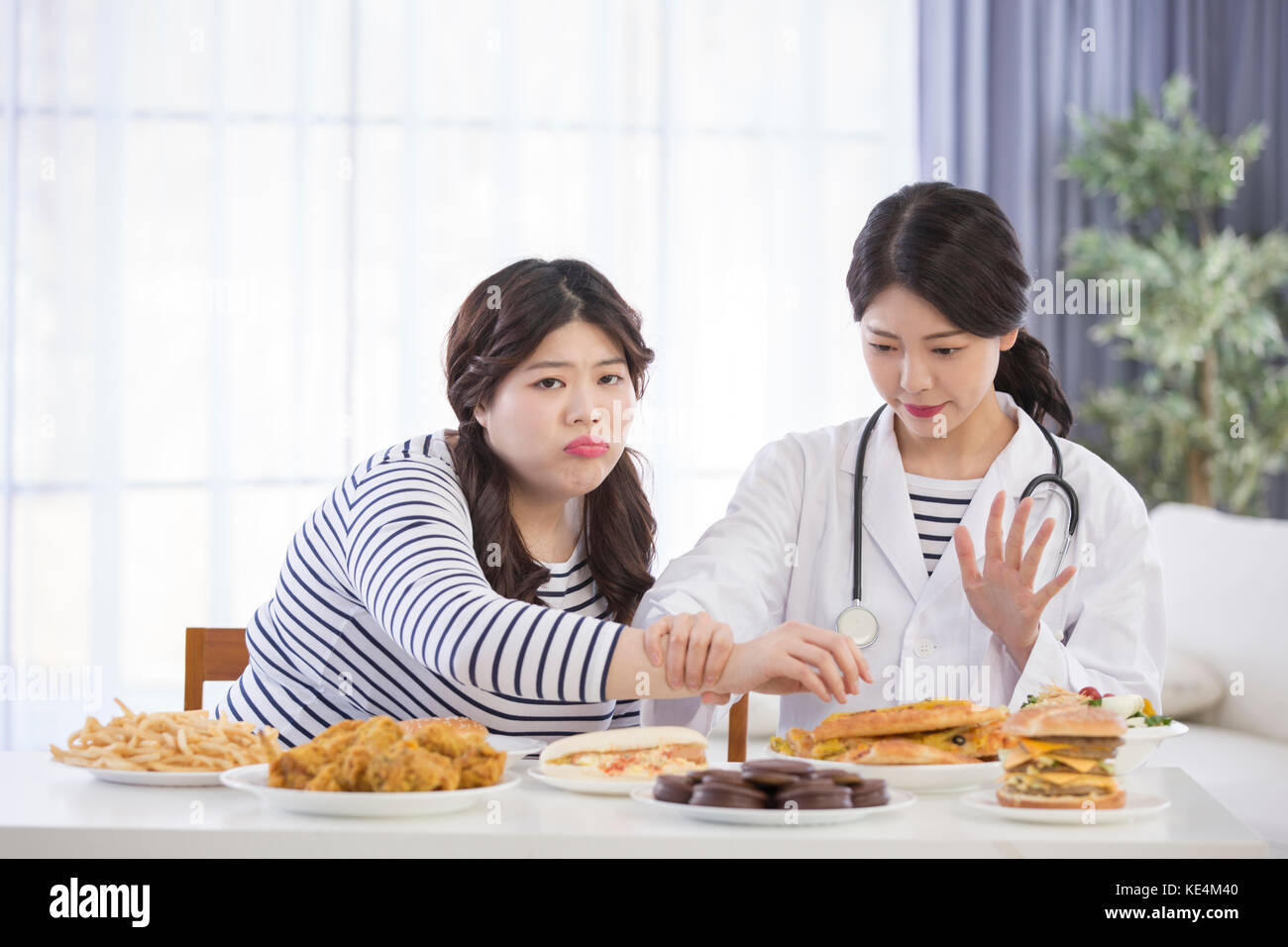 Portrait of young fat woman trying to eat fast-food and a nutritionist ...