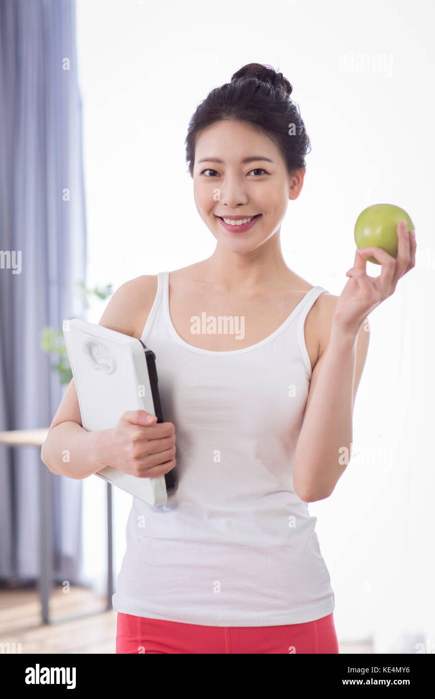 Young smiling slim woman with a scale and an apple posing Stock Photo ...